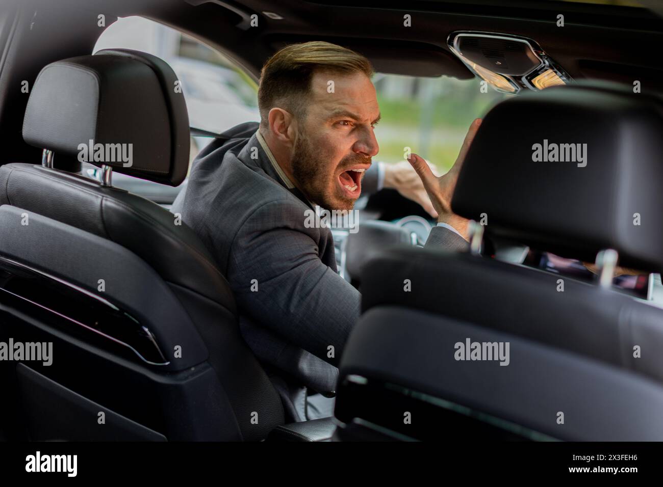 An angry man in a suit yelling while behind the wheel in gridlocked ...