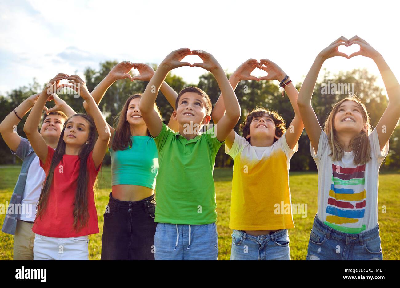 Happy children making heart shapes with their hands raised Stock Photo ...