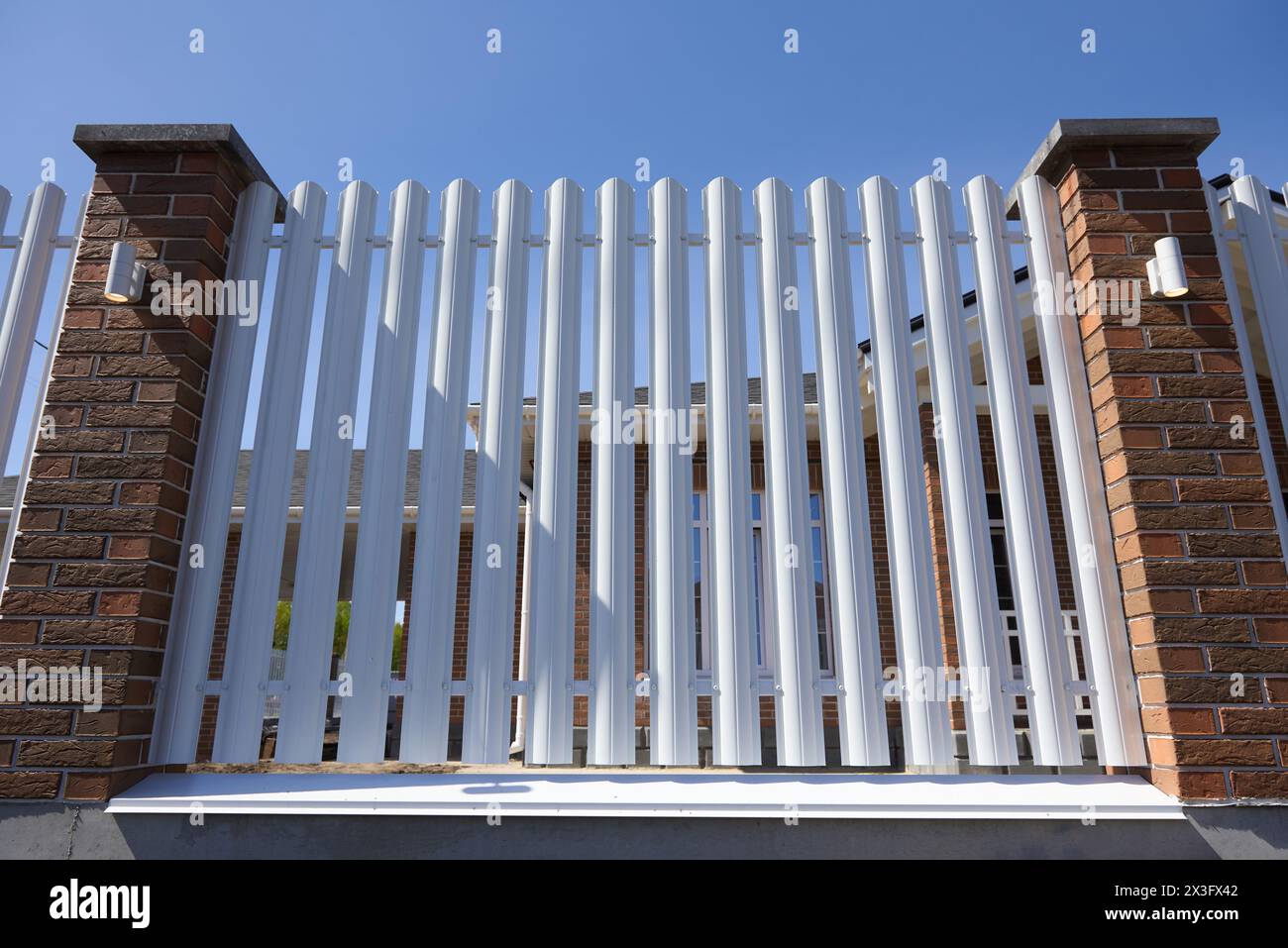 Modern white picket fence with brick posts Stock Photo - Alamy
