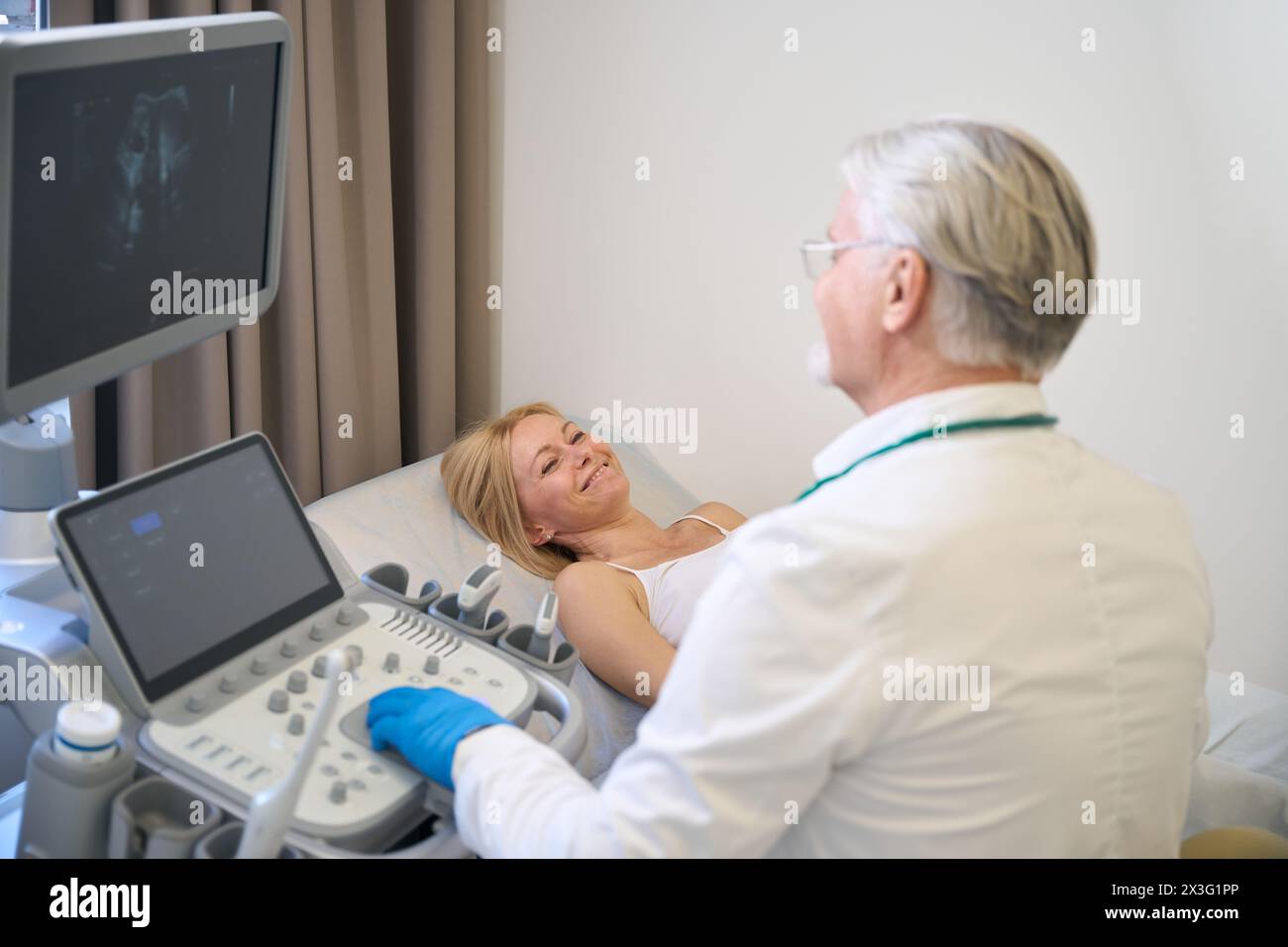 Doctor using ultrasound scan examining smiling woman Stock Photo - Alamy