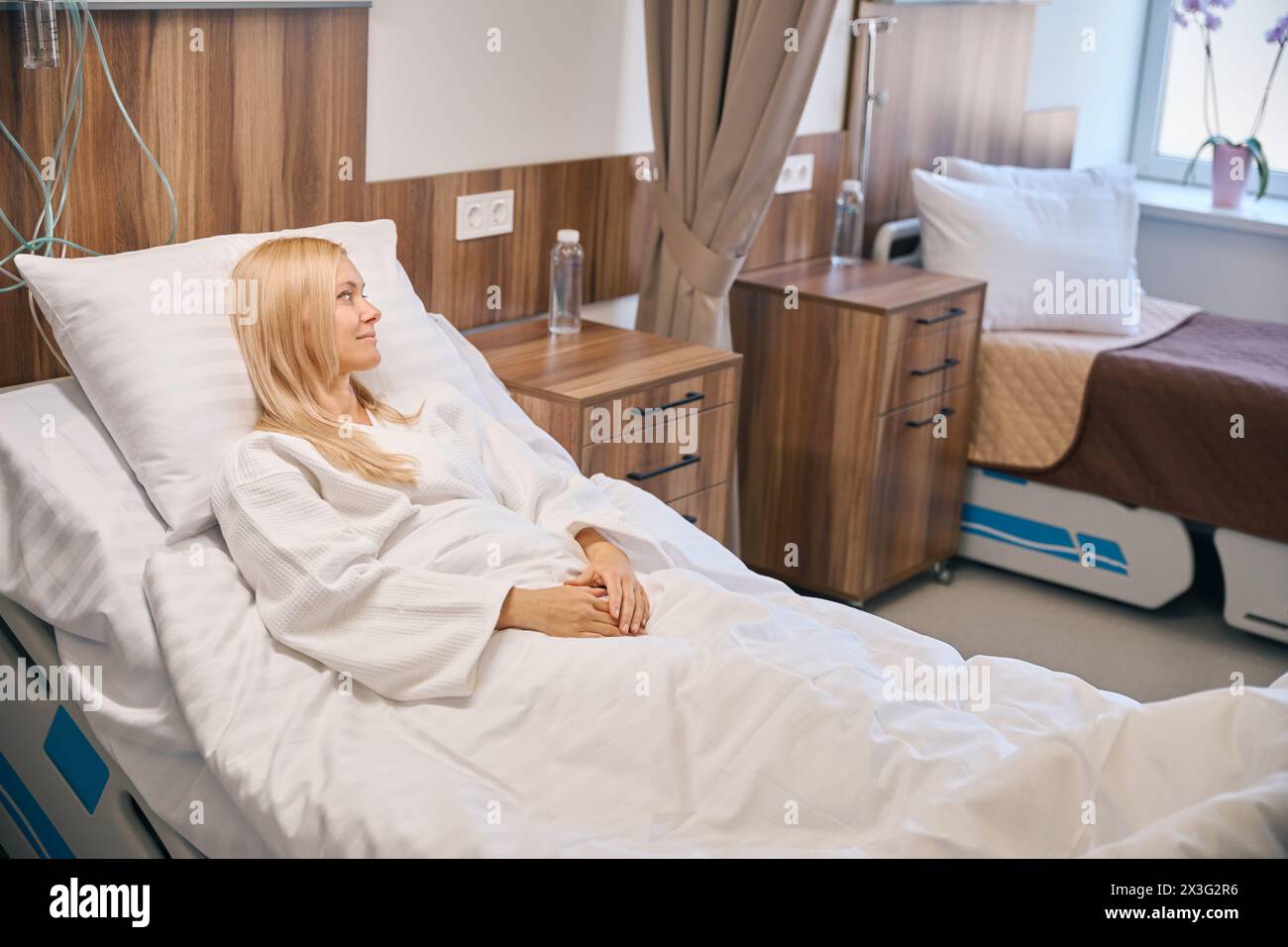 Hospitalized smiling woman lying in hospital bed Stock Photo - Alamy