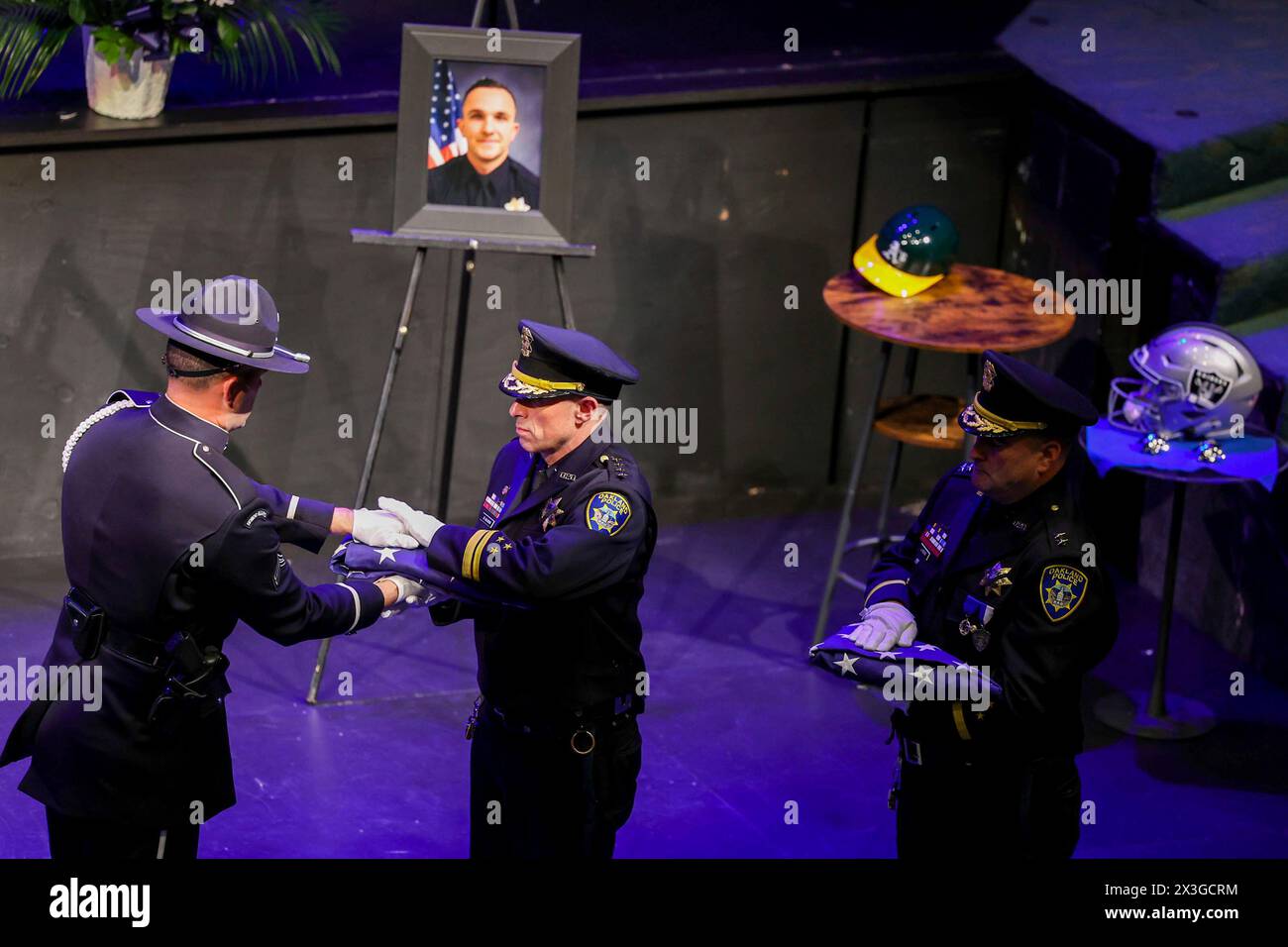 An officer from the Oakland Police Honor Guard hands over a folded ...