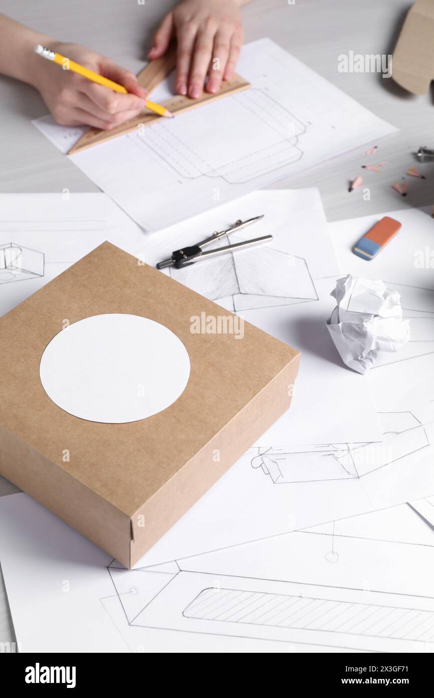 Box and stationery on drawings, closeup. Woman creating packaging ...