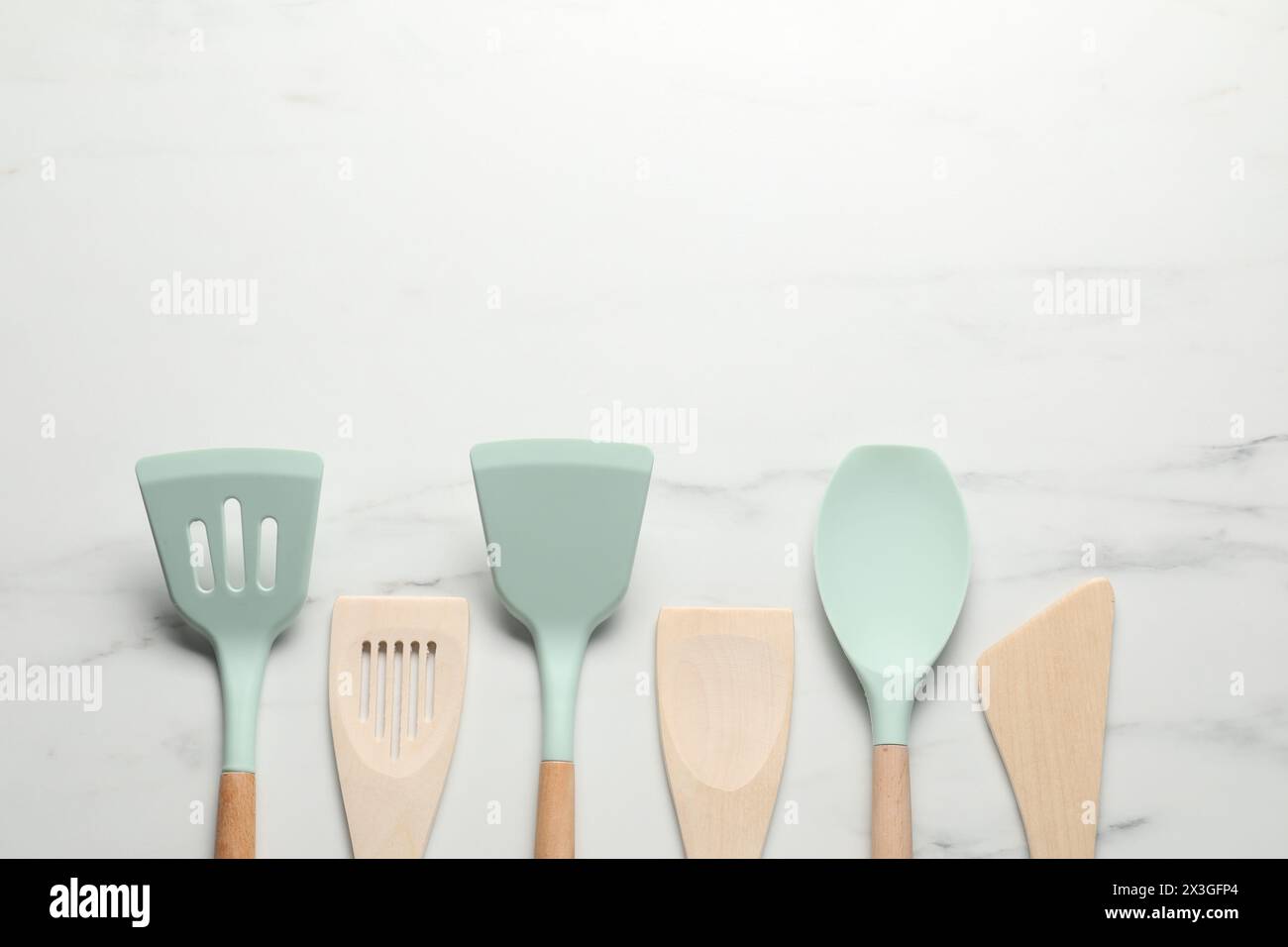 Different spatulas on white marble table, flat lay. Space for text ...