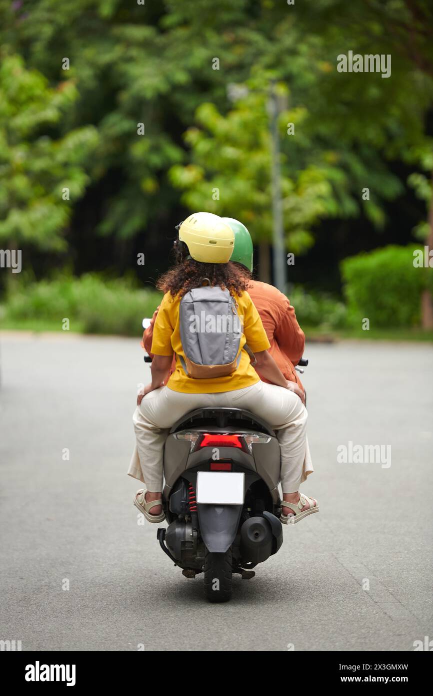 Back view of young woman with backpack sitting on motorcycle and ...
