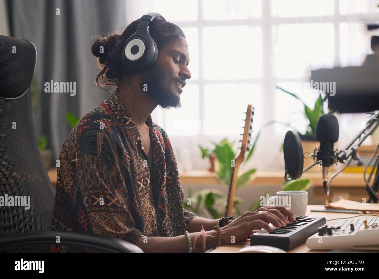 Happy young singer and songwriter pressing keys of electric piano and ...