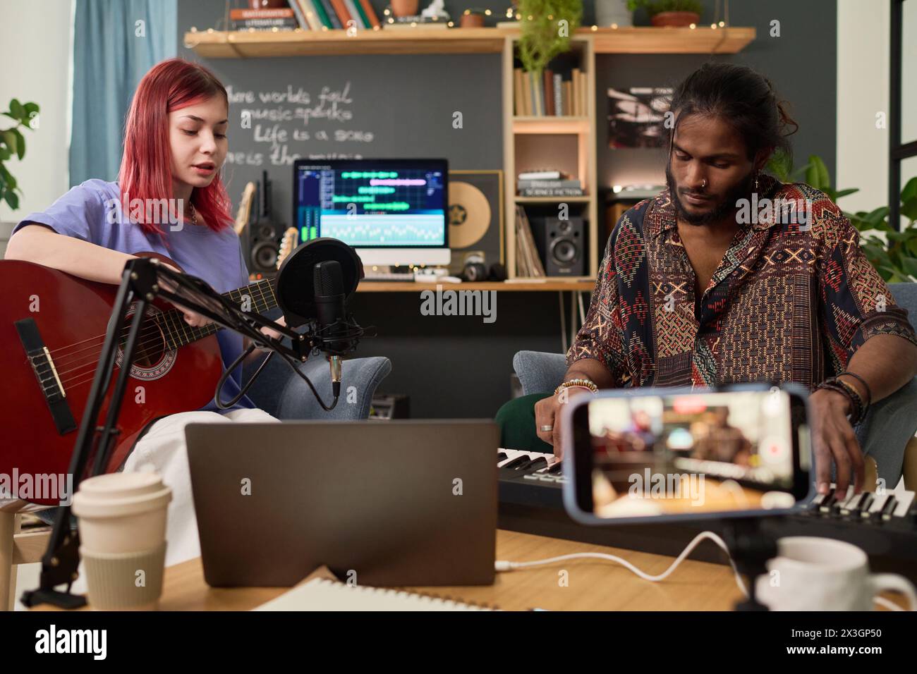 Two young creative musicians playing synthesizer and acoustic guitar ...