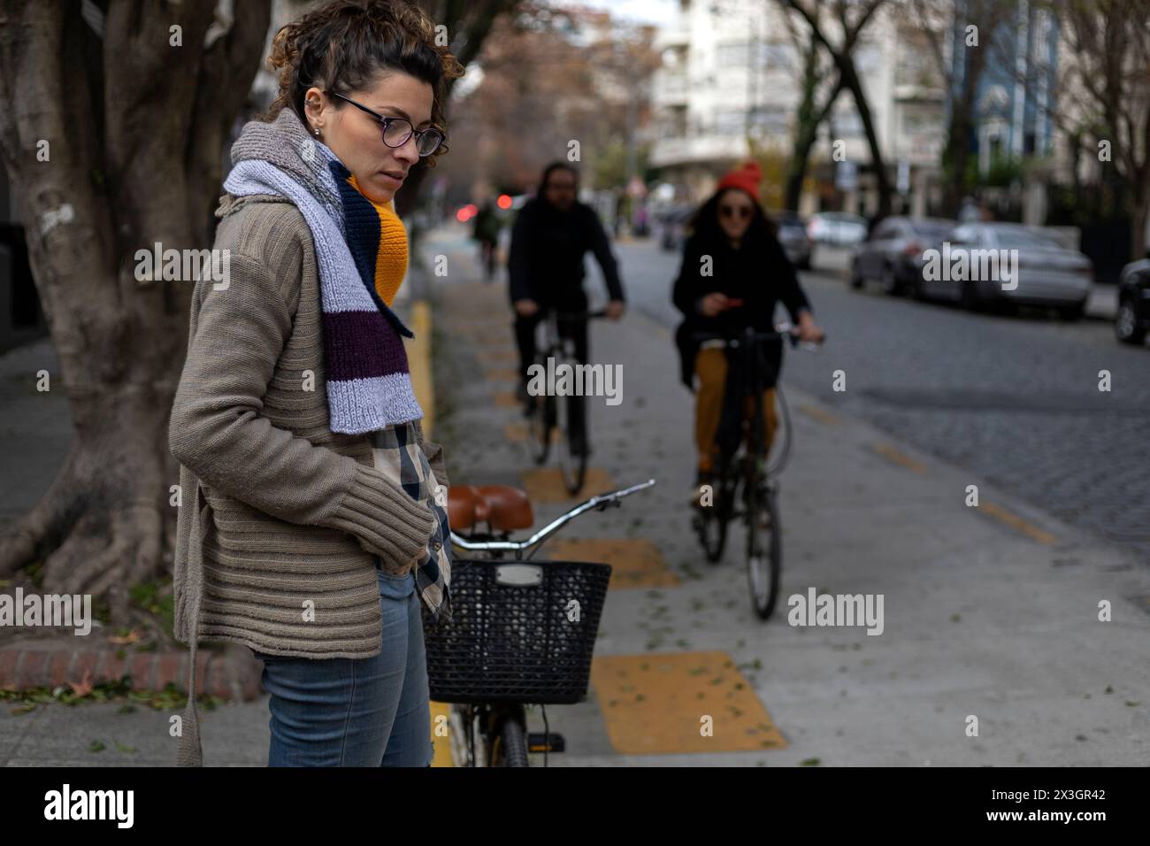 A young Latin American woman waits on the side of the bike lane as ...