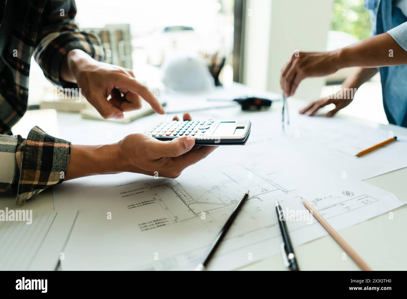 Two engineer use scientific calculator and geometry compass to drawing ...