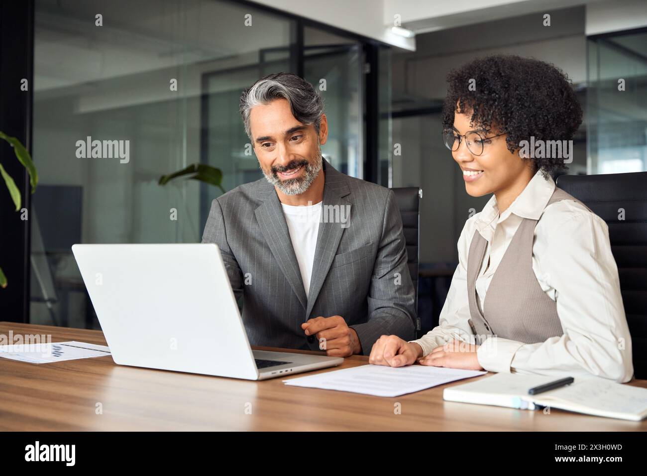 Two happy busy diverse business people talking using laptop working in ...