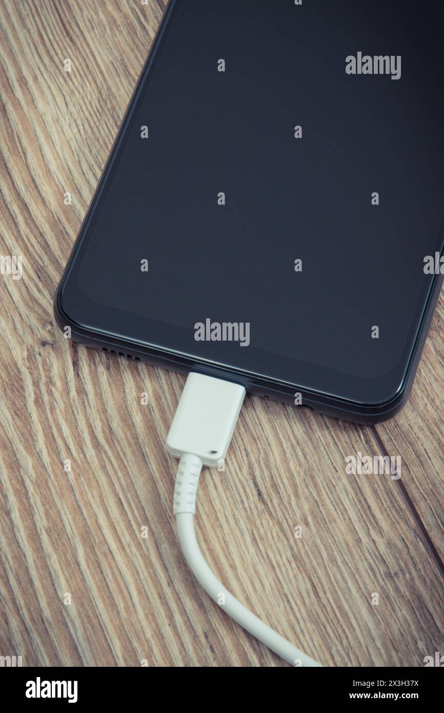 Black smartphone and connected cable of charger. Mobile phone charging ...