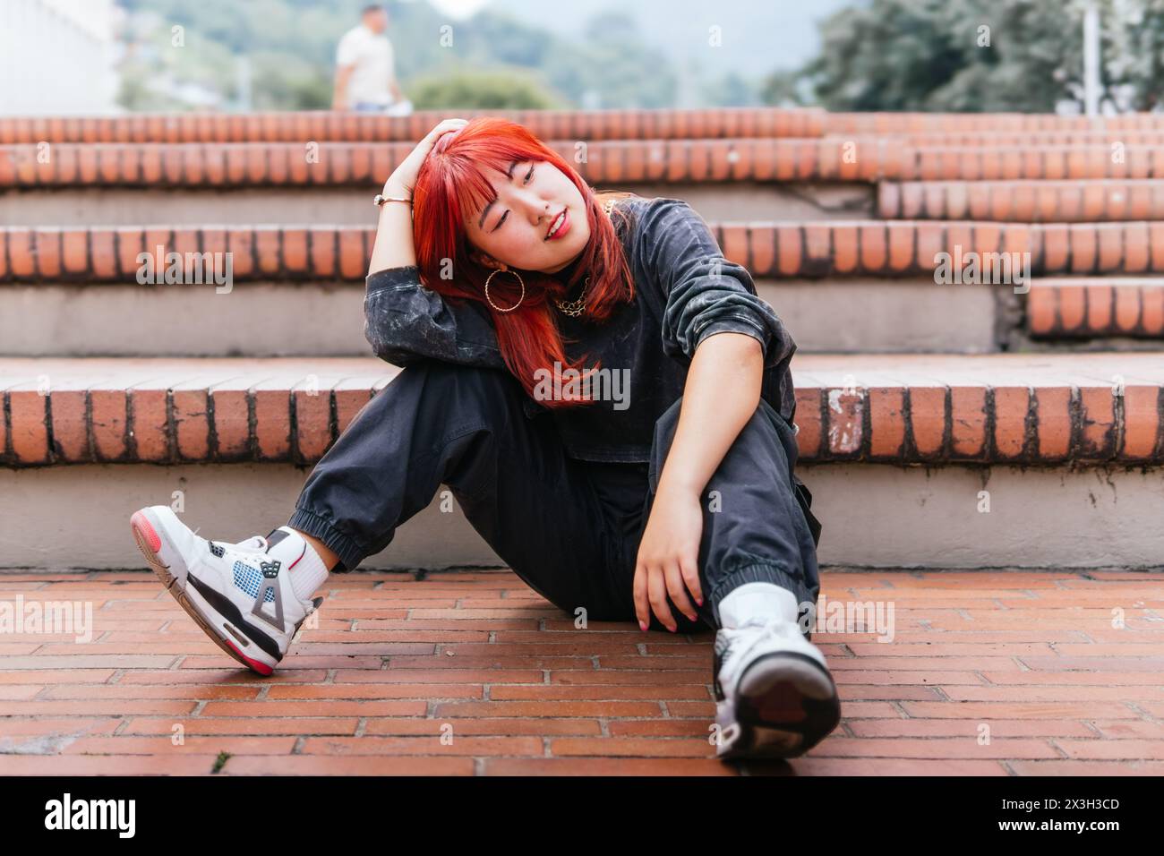 Korean woman with red hair seated on steps, in a reflective pose Stock ...
