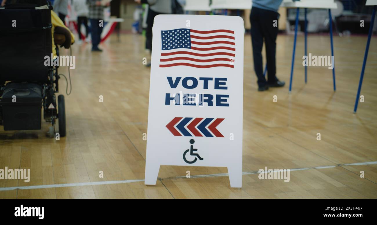 Vote here sign on floor. Woman with spinal muscular atrophy in electric ...