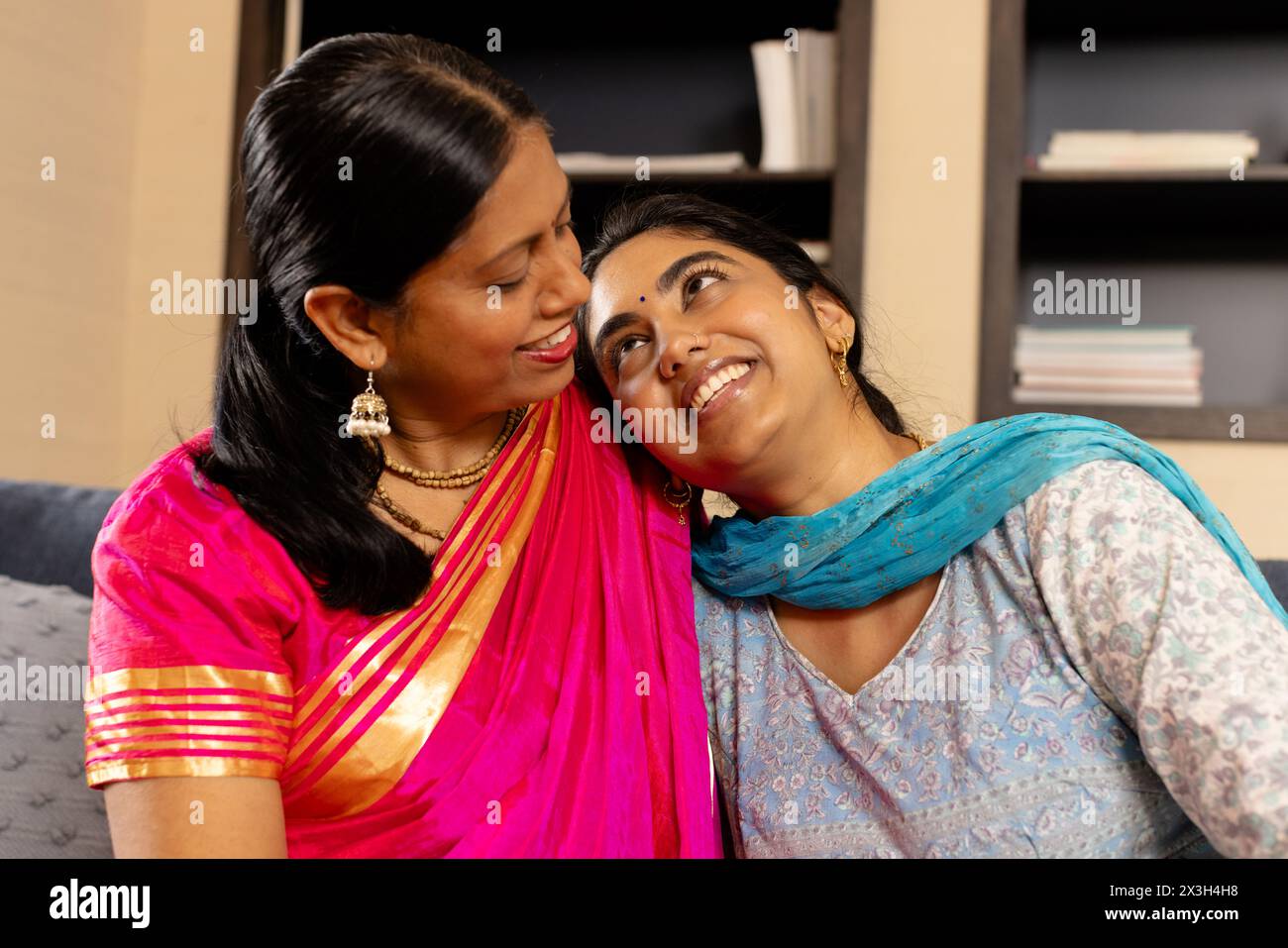 Indian mother and teenage daughter, sitting close at home, sharing warm ...
