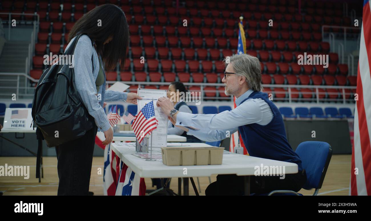 African American girl talks with polling officer, takes bulletin ...