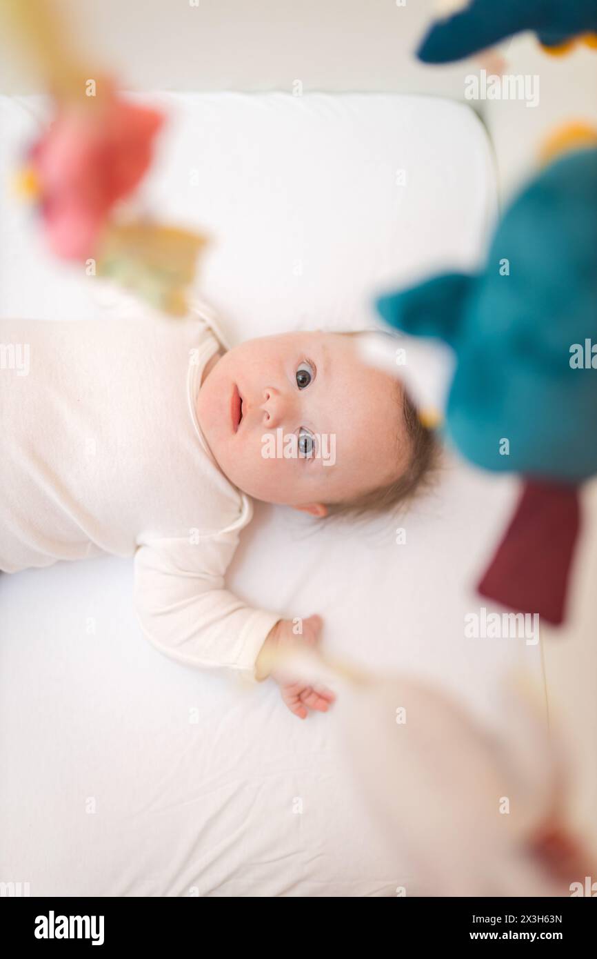 Cute Baby Girl Infant Stand in her bed, looking at the suspended toy ...