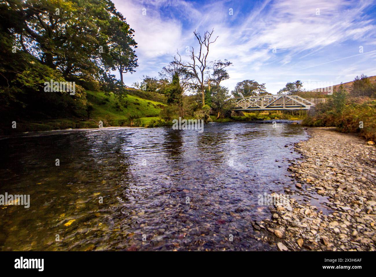 The clear water of the Aflon Glaslyn (River Glaslyn) with an Iron truss railway bridge in the ...