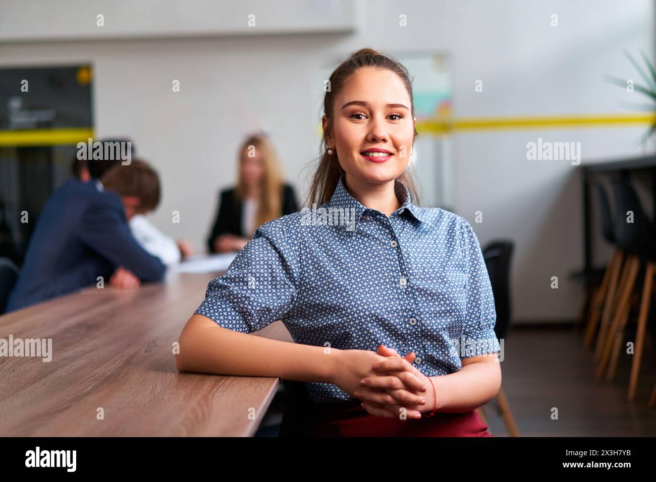 Confident Asian businesswoman sits at office desk, smiles at camera ...