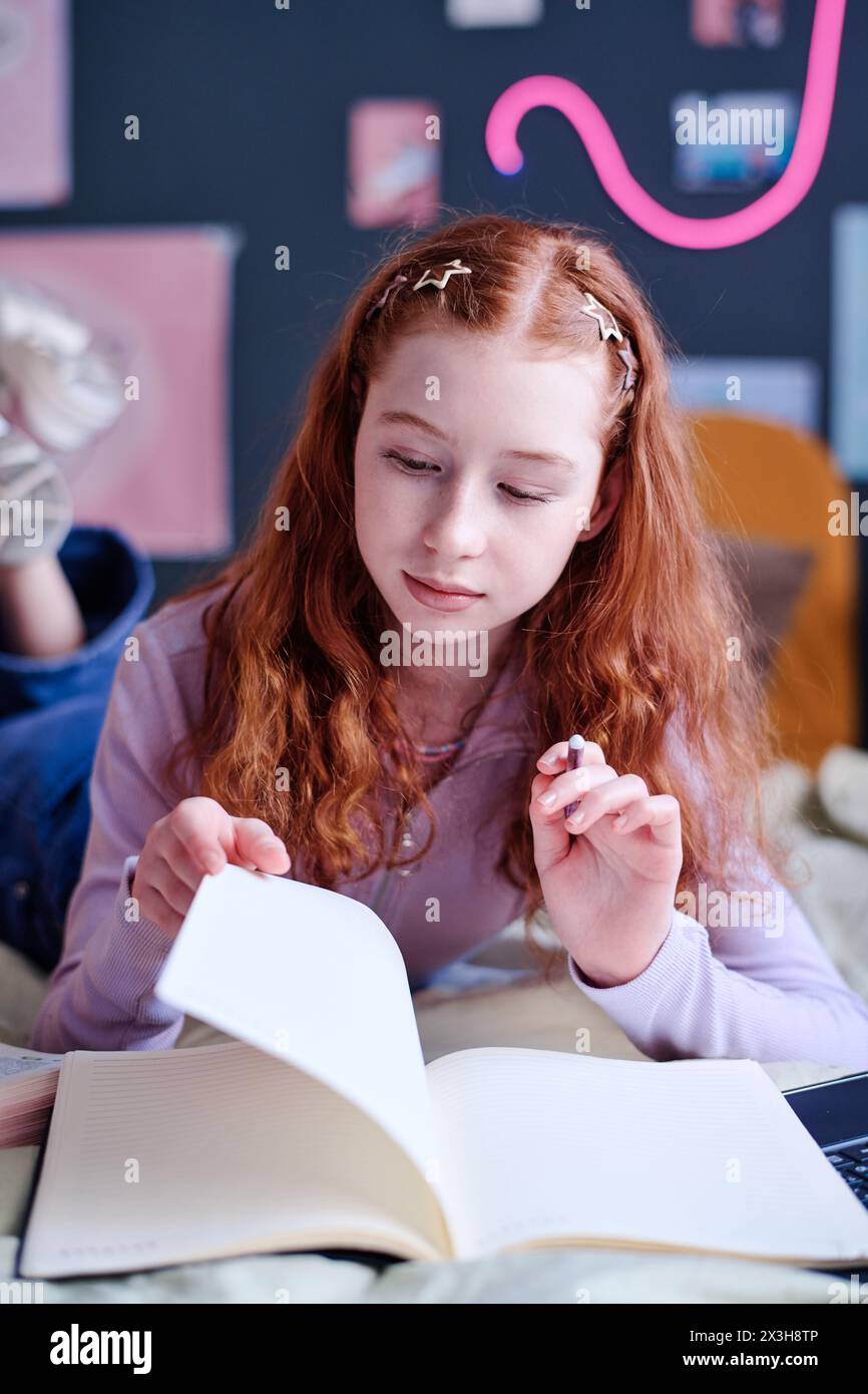 Vertical medium closeup of modern teen girl looking through notes in ...
