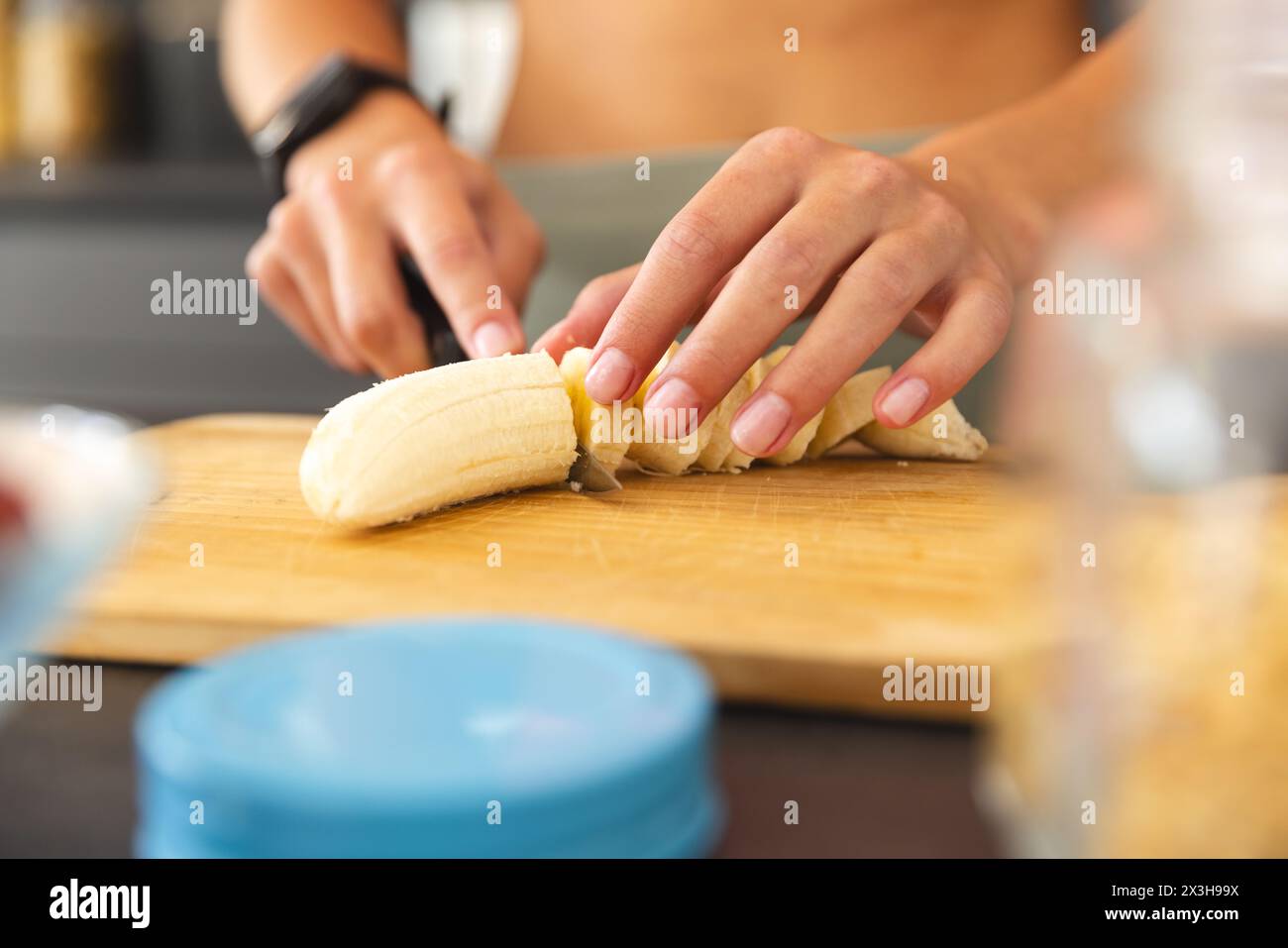 A young Caucasian woman slicing banana on cutting board at home Stock ...