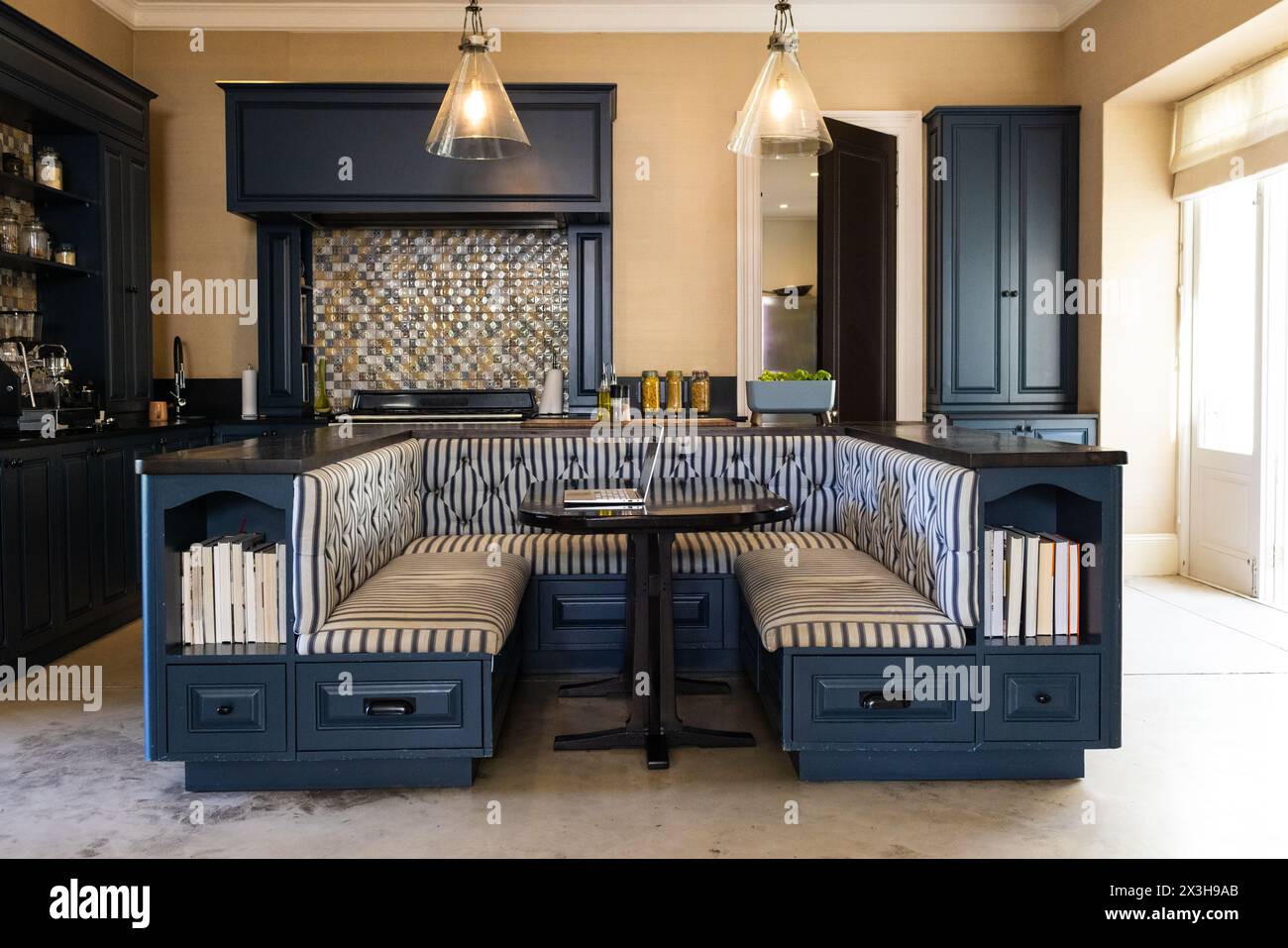 A modern kitchen with dark cabinets and cozy booth-style seating area ...