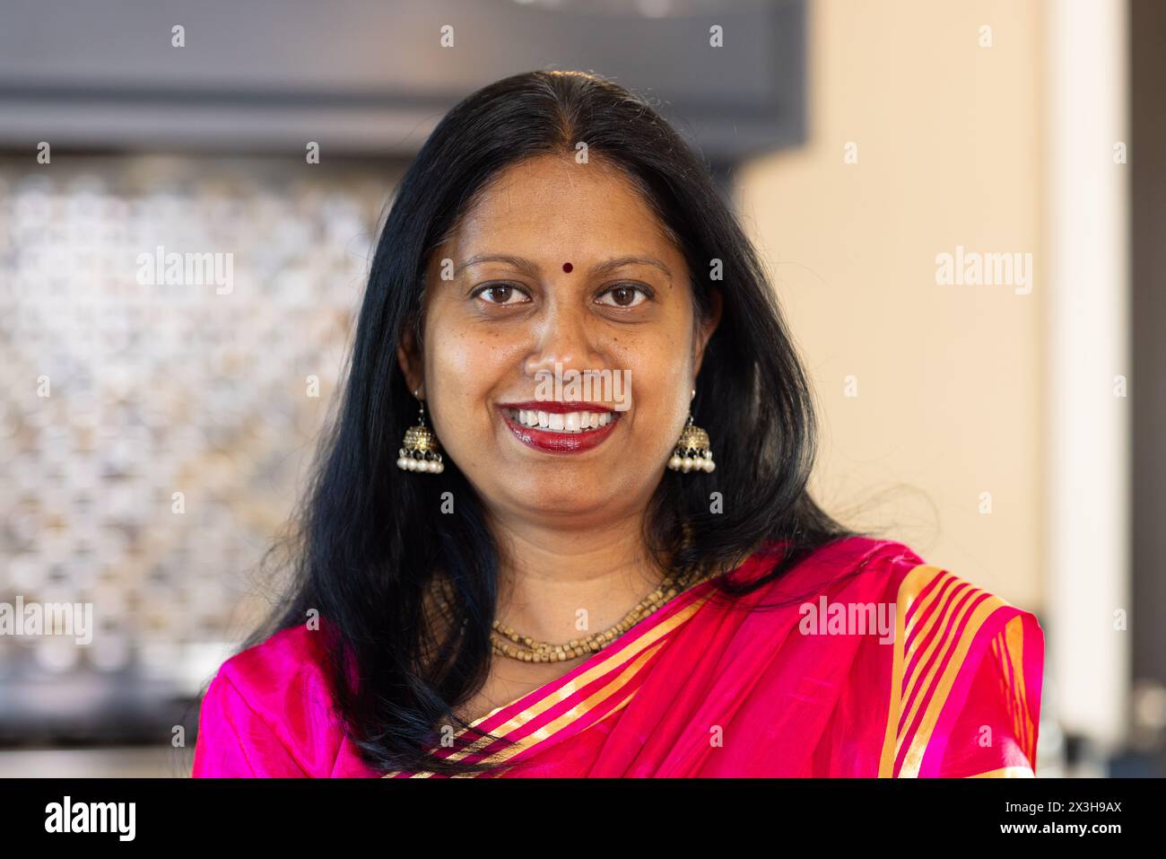 Indian woman wearing bright red saree, smiling at camera at home Stock ...
