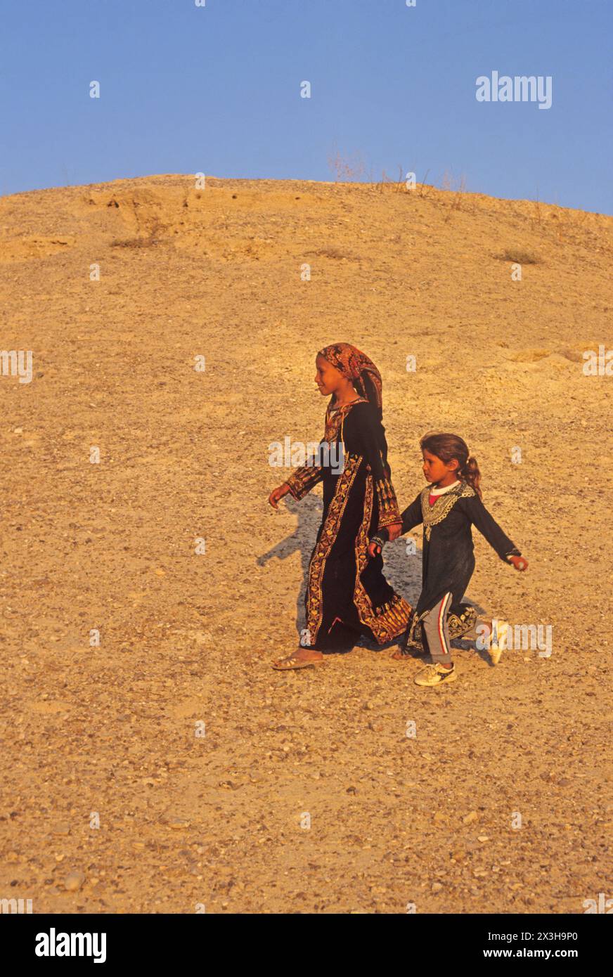 Bedouin girls walking in the desert Stock Photo - Alamy