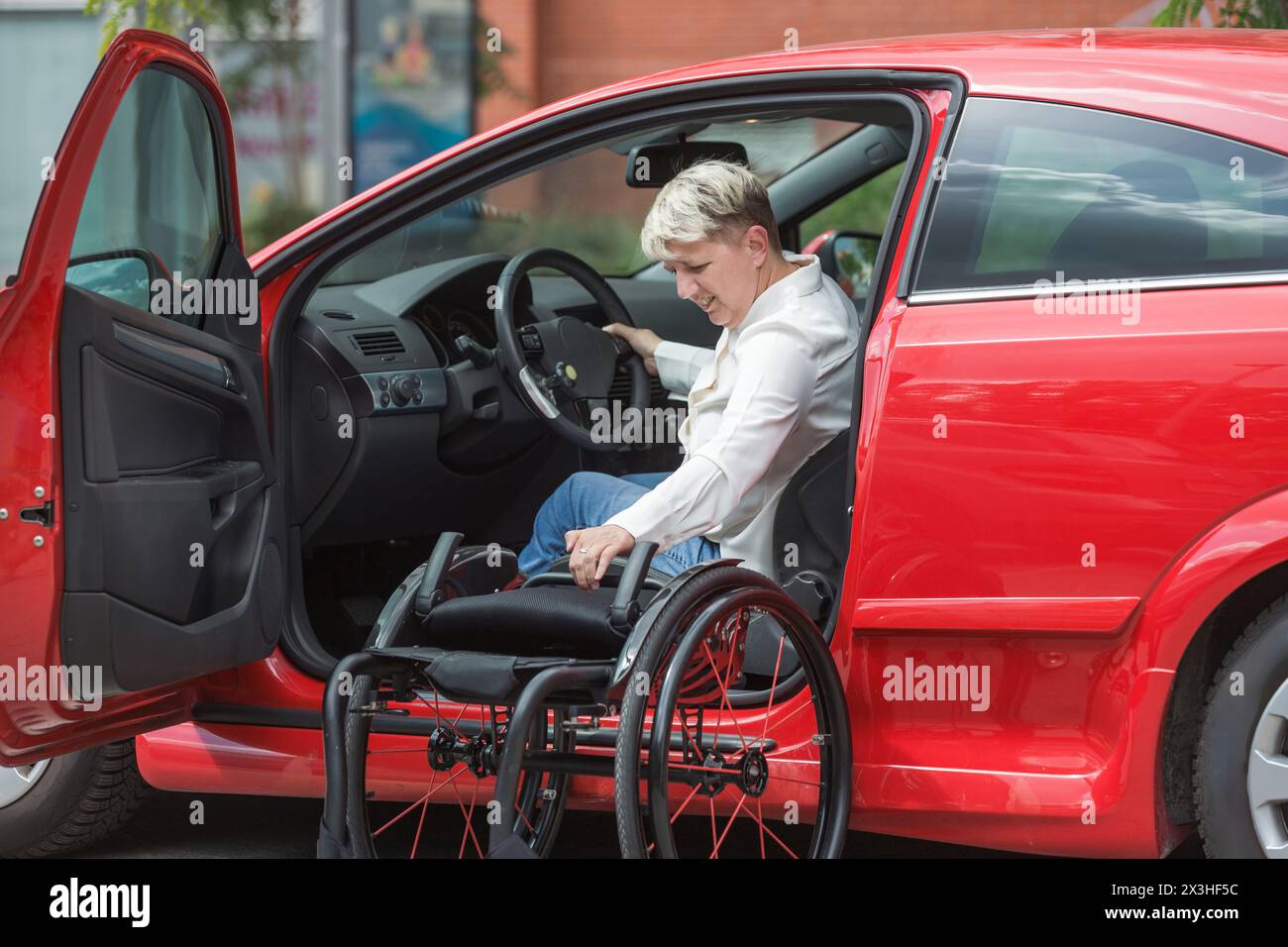Businesswoman, a driver with a disability getting into a red car ...