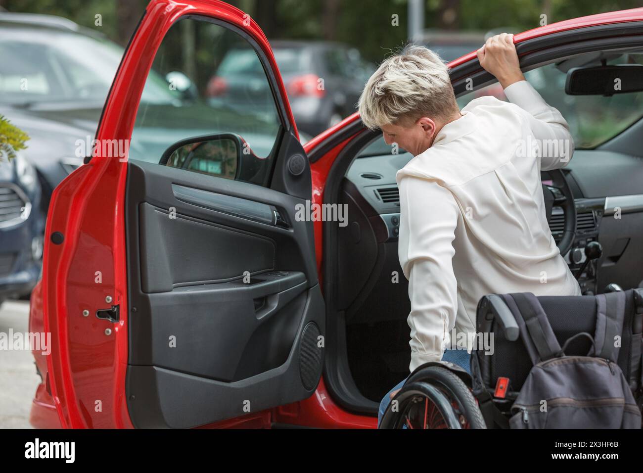 Female driver with disability entering a car, a wheelchair user on the ...