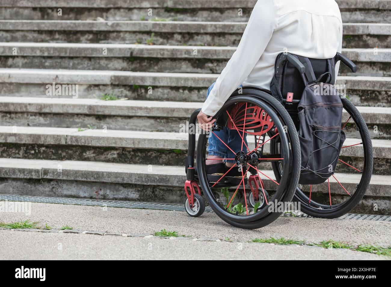 Woman in a wheelchair stopping and waiting at the bottom of inacessible ...