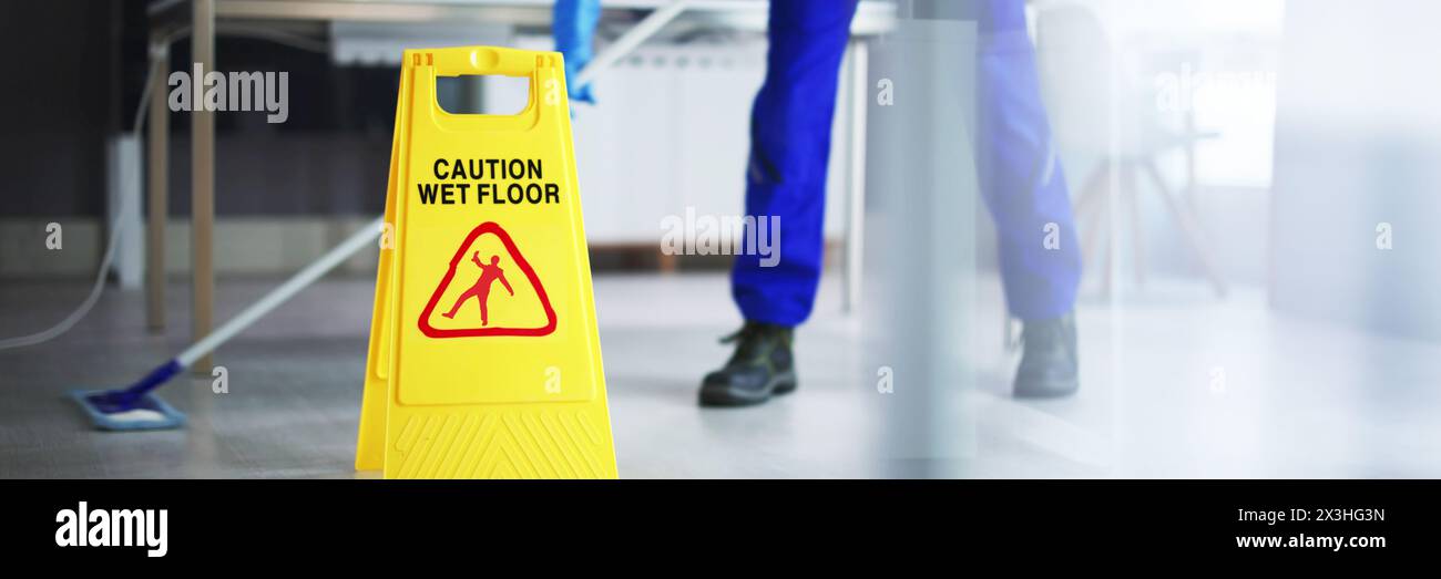 Janitor cleaning a wet floor with cleaner sign Stock Photo - Alamy