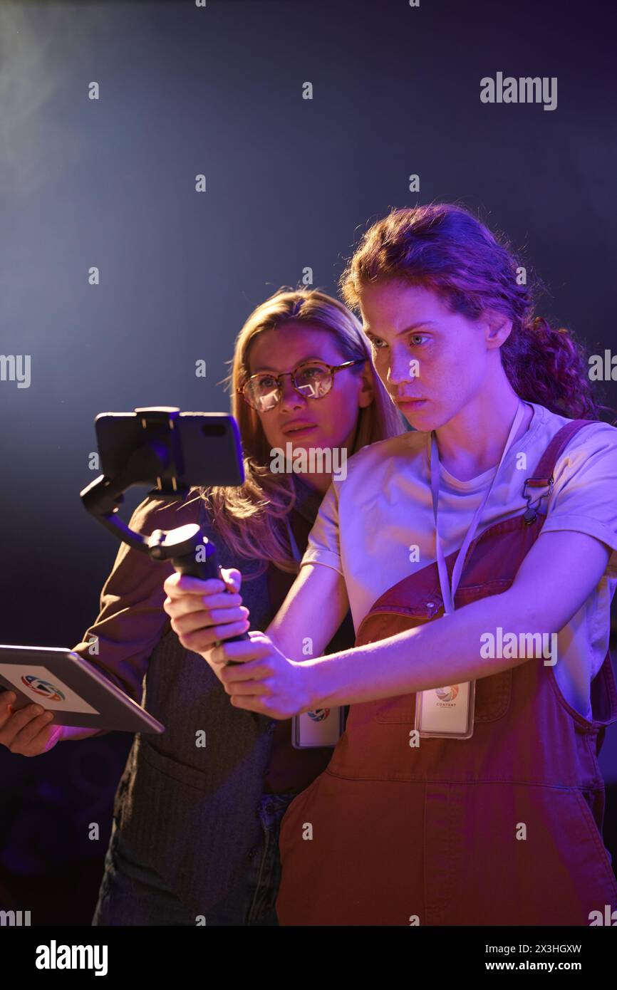 Vertical portrait of two women filming videos via smartphone for social ...