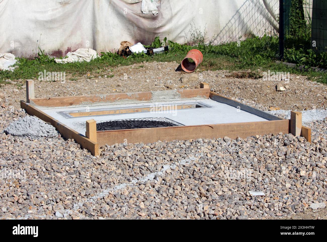 Freshly poured concrete around metal sewer manhole cover held together ...