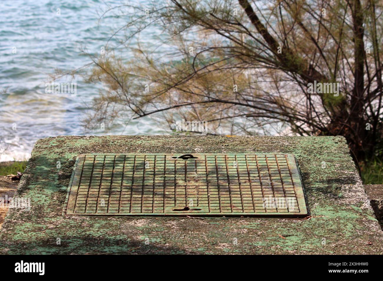 Heavy closed rectangular metal manhole cover with concrete foundation ...