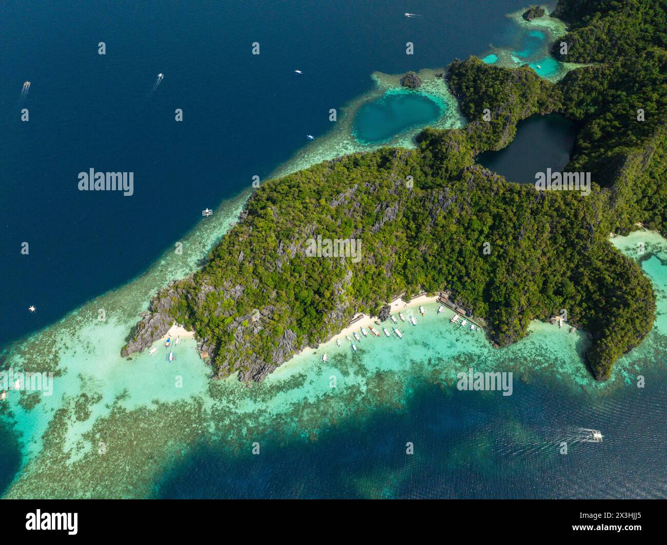 Banul Beach with white sands and boats over clear water. Black lake in ...