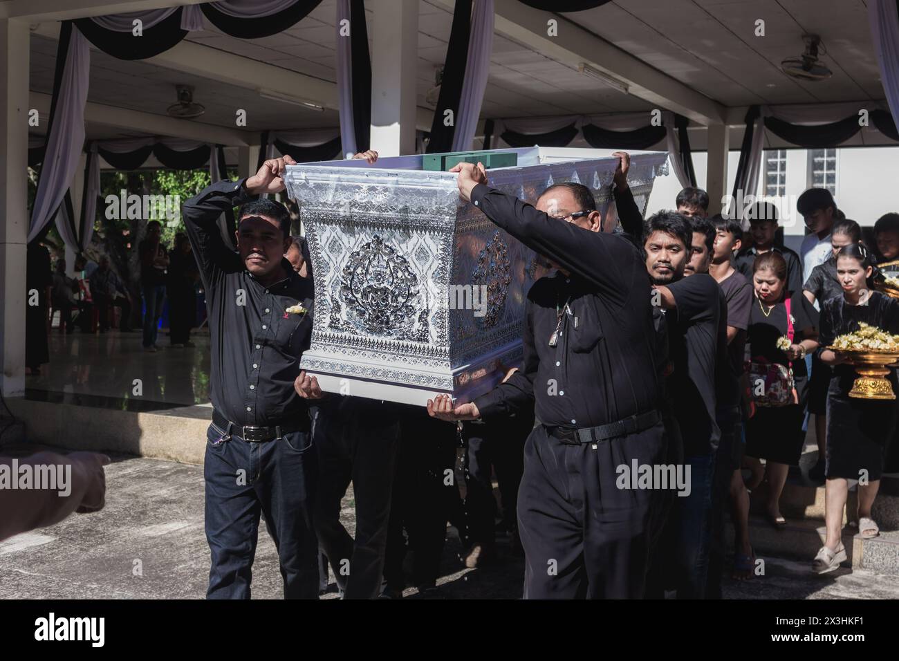 Phatthalung, Thailand- April 05, 2024: Man in black is helping to carry the coffin of the ...