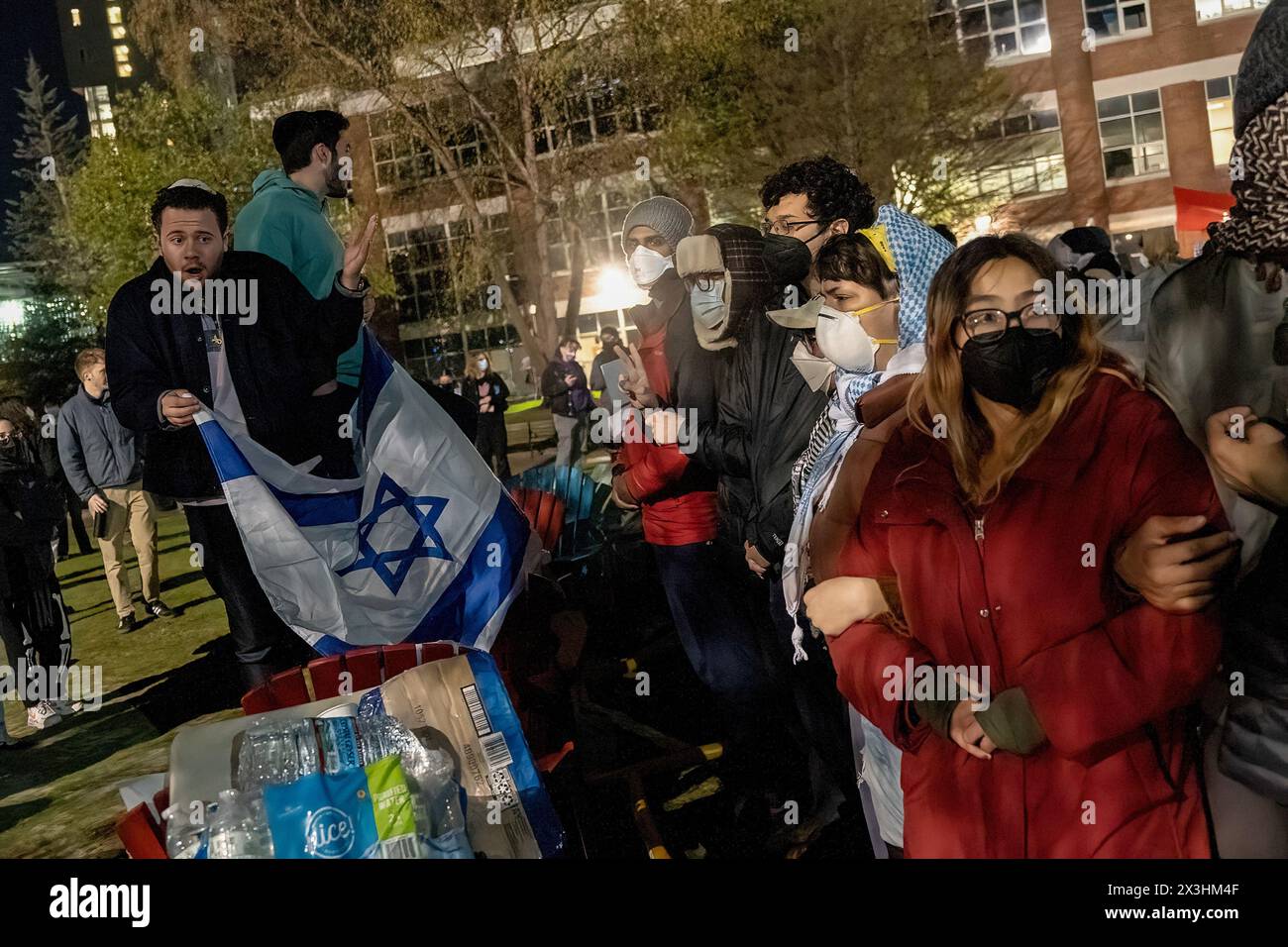 Pro-Palestine protesters lock arms on the edges of the encampment while ...