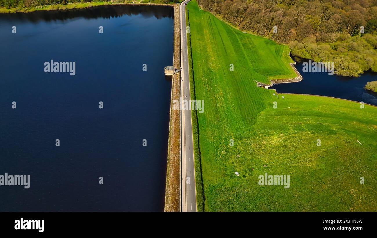 Aerial view of a dam separating a river and a lush green field ...
