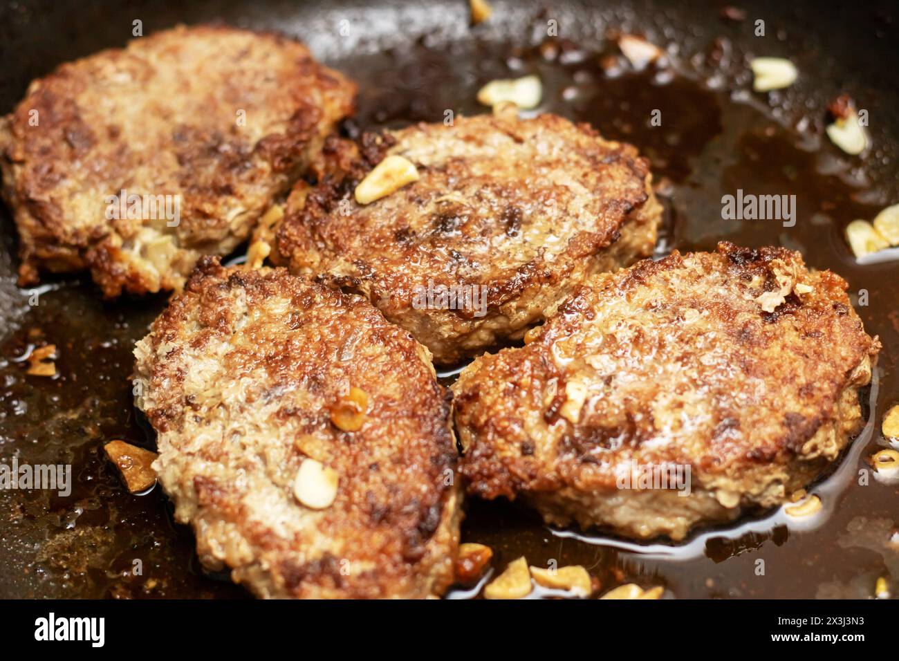 A cut of meat is sizzling in a frying pan, being cooked to perfection ...