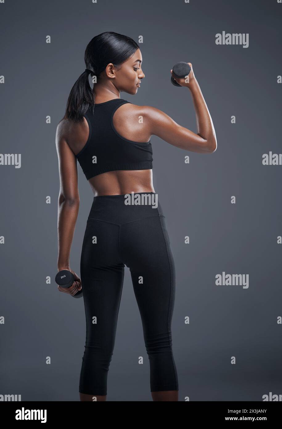 Indian woman, dumbbells and exercise for fitness in studio on grey ...