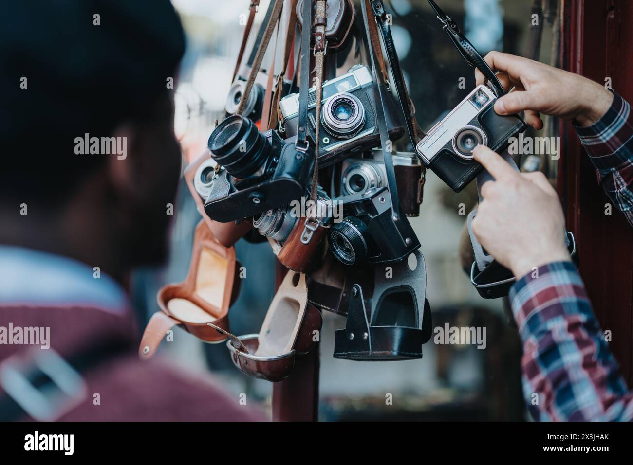Man examining vintage cameras hanging at an outdoor market Stock Photo ...