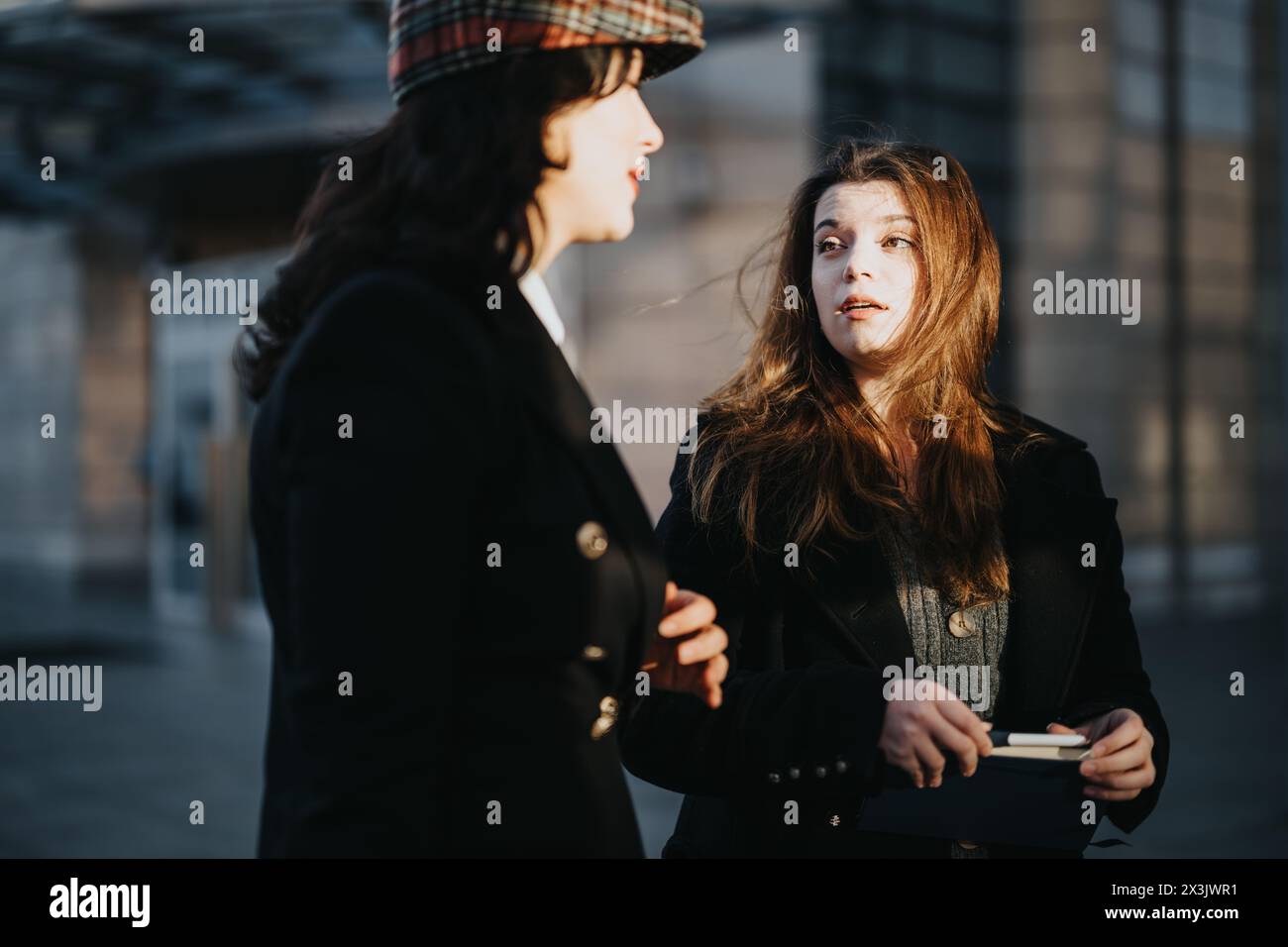 Two young women having an intense discussion outside with a blurred ...