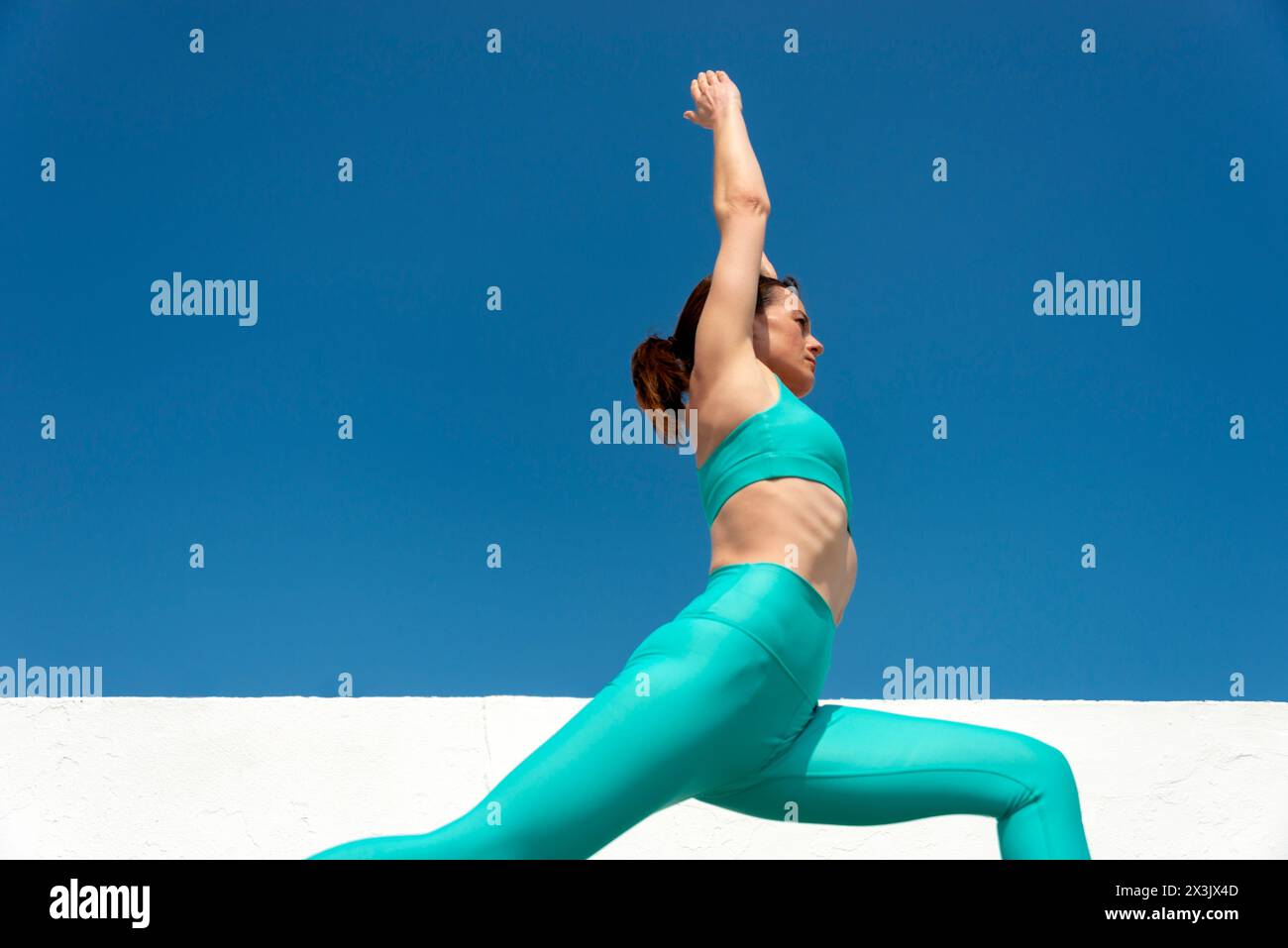 Side view of woman wearing green sportwear doing yoga exercise with ...