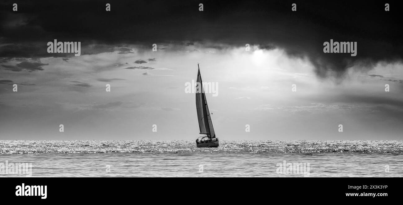Black and white photograph of a sailboat sailing in a dramatic sunset ...