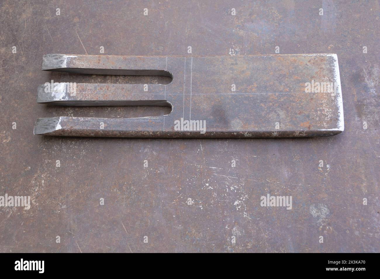 A flat rectangular piece of steel with three symmetrical tine tools ...