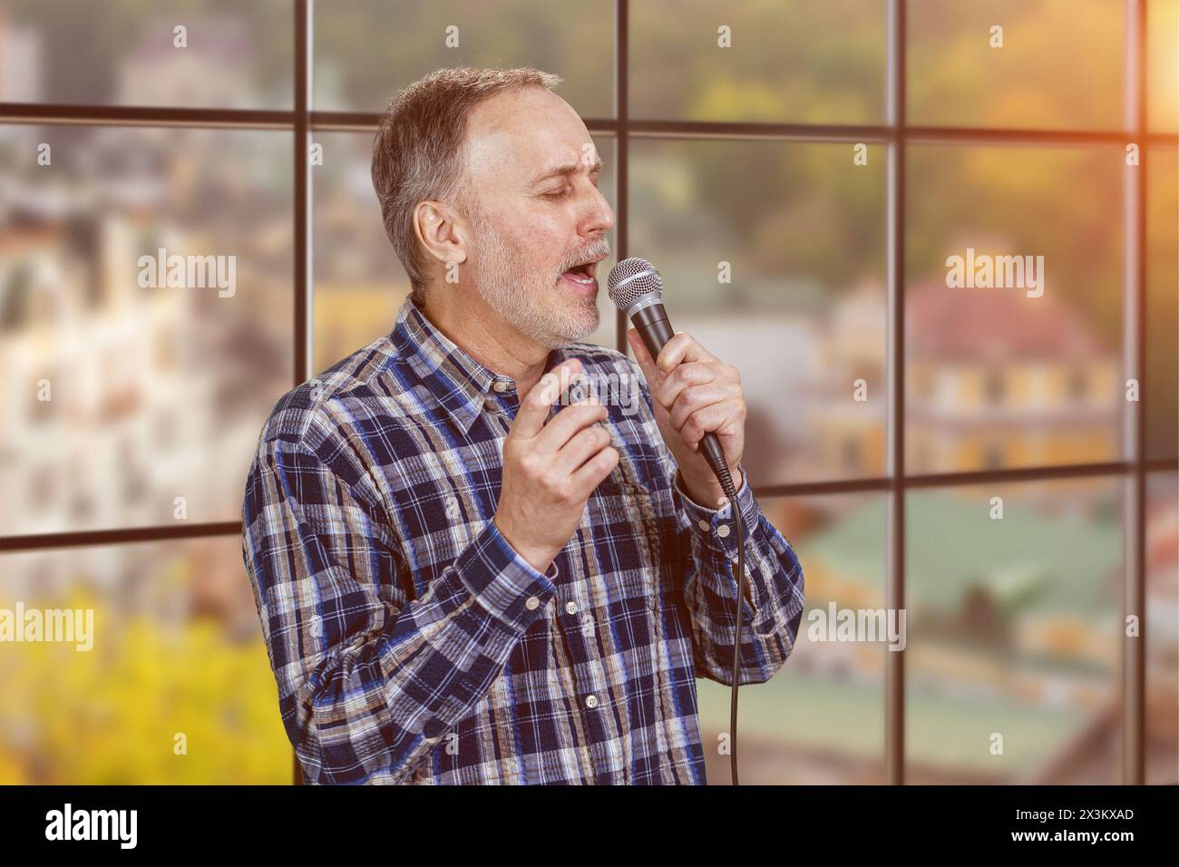 Expressive handsome mature man is singing in microphone. Checkered ...