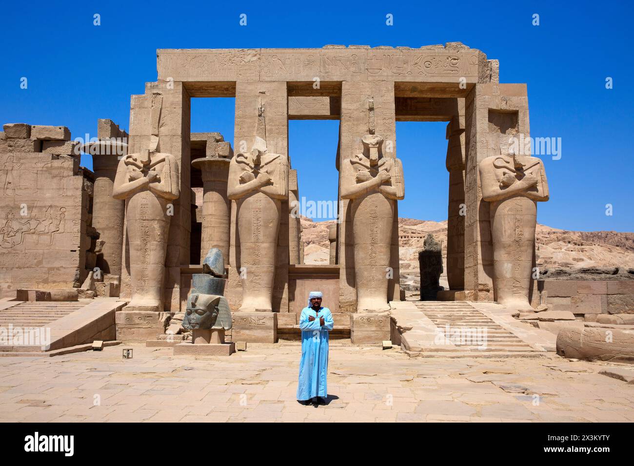 An Egyptian man in traditional attiire posing in front of the Osiride ...