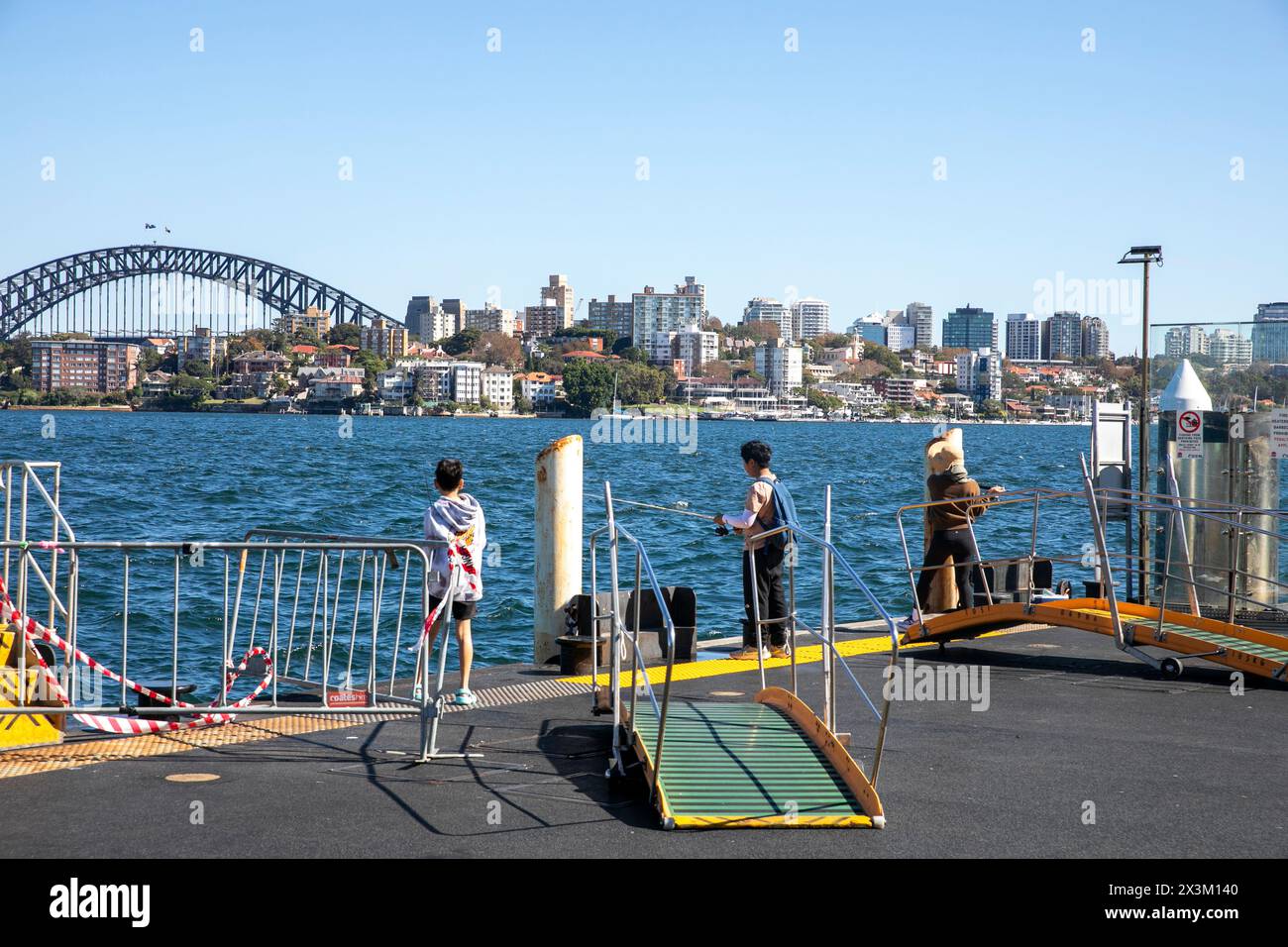 Asian mother and two young sons fishing with fishing rods off Cremorne ...