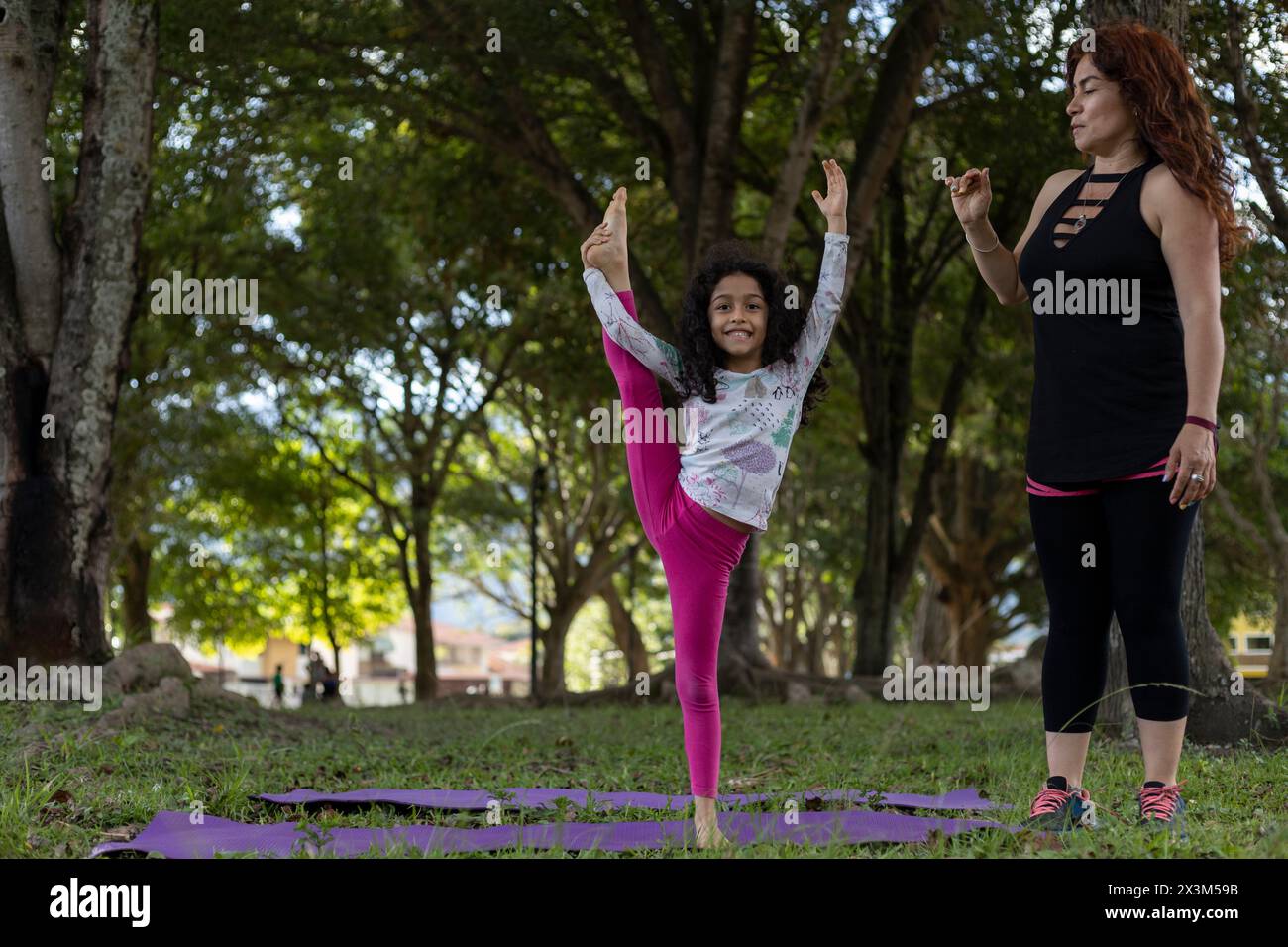 Latin American mom and daughter have fun in the park doing balancing ...