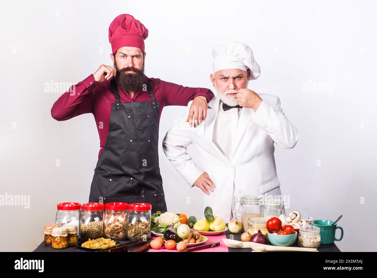 Two professional chefs in cook uniform and hat preparing delicious food ...